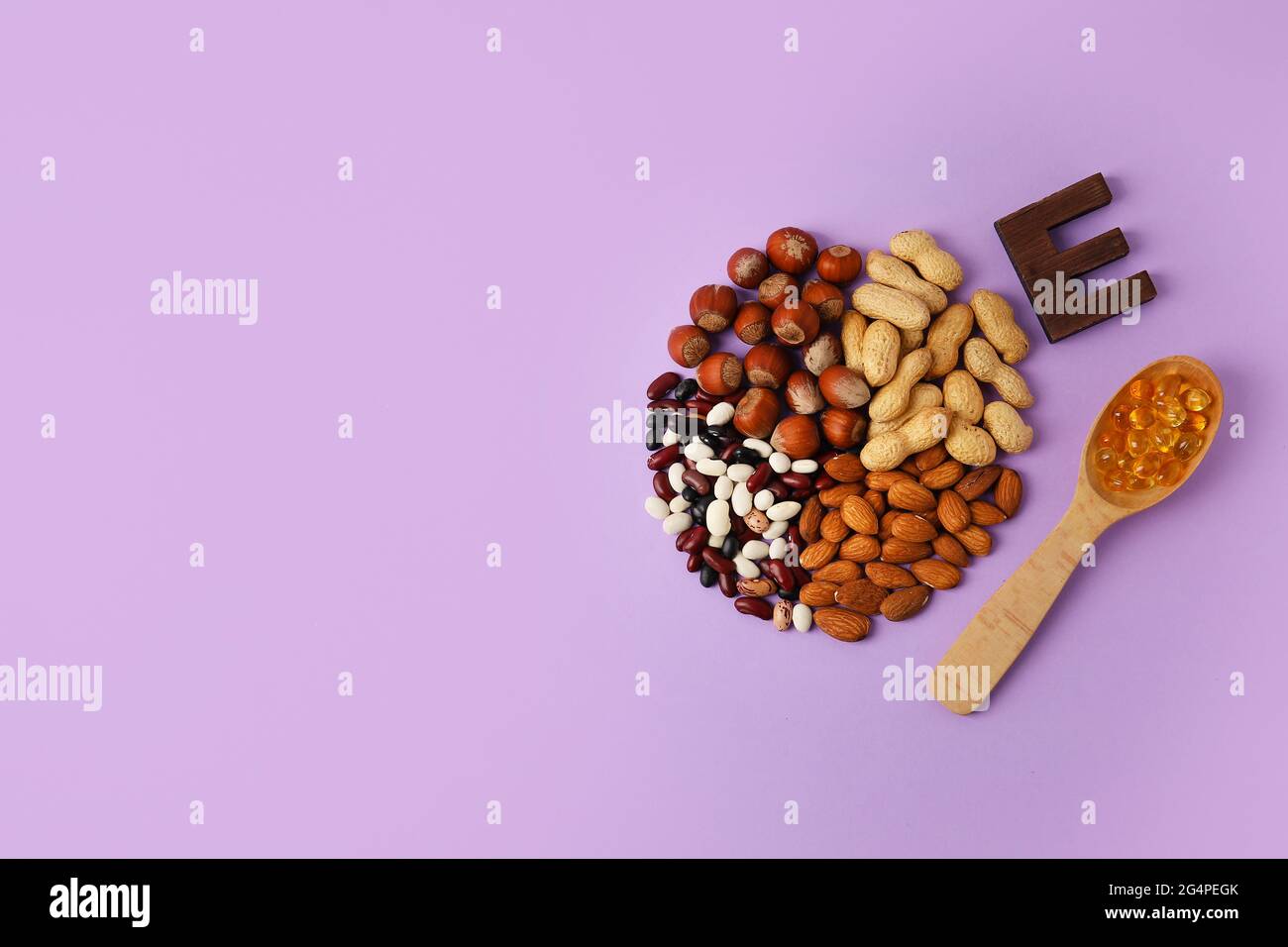 Letter E, different healthy nuts and fish oil capsules on color ...