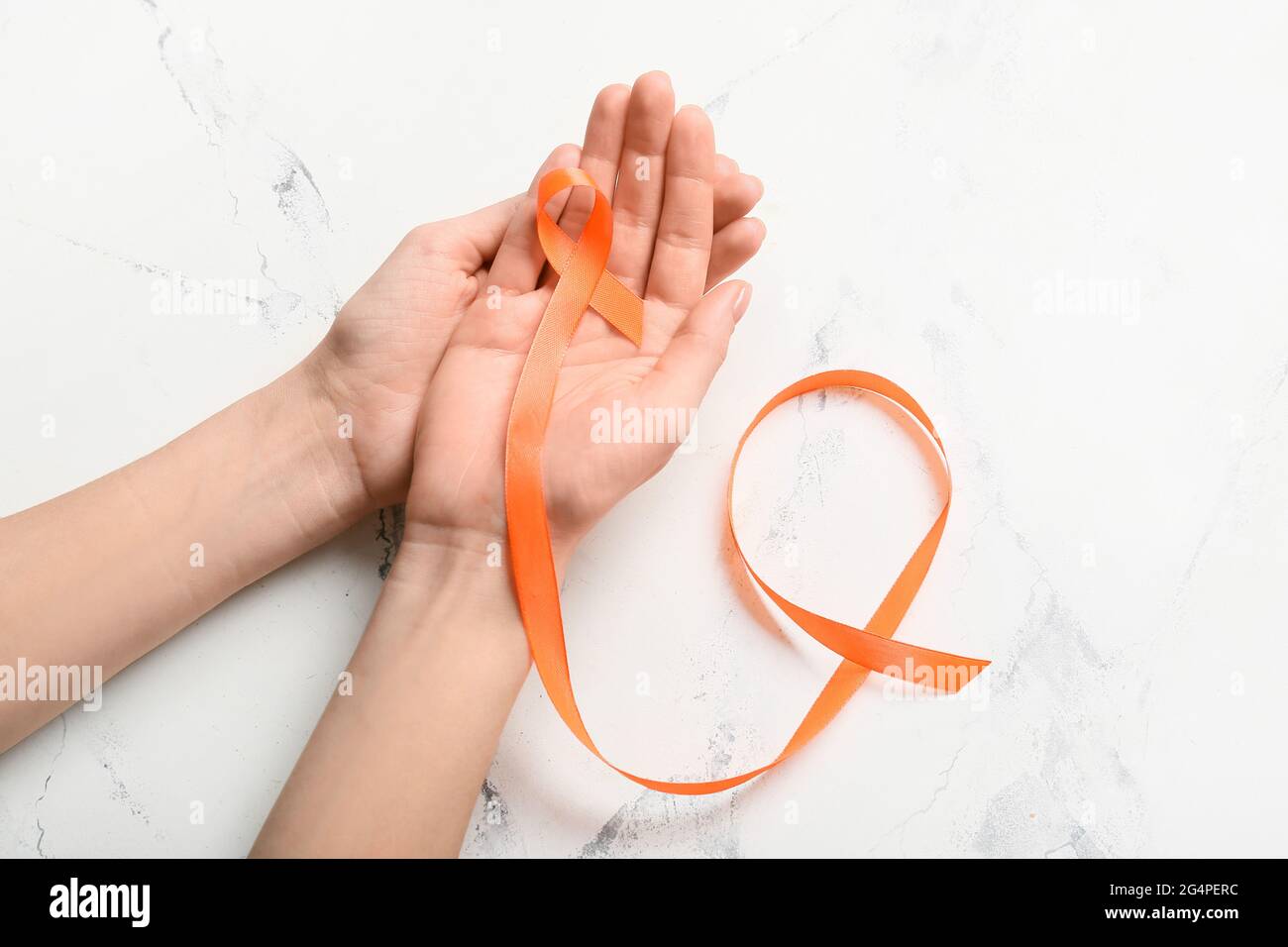 Female hands with orange ribbon on light background, closeup. Cancer ...