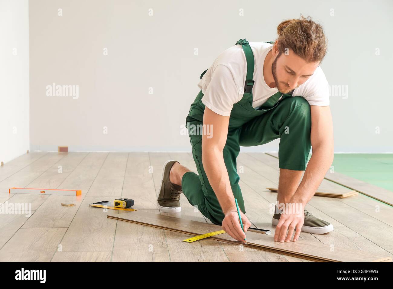 Carpenter installing laminate flooring in room Stock Photo - Alamy