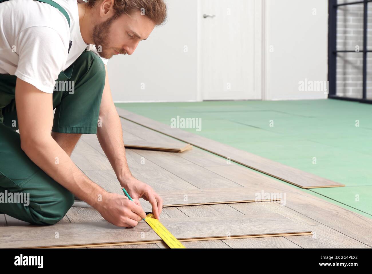 Carpenter taking measurements of laminate flooring in room Stock Photo ...