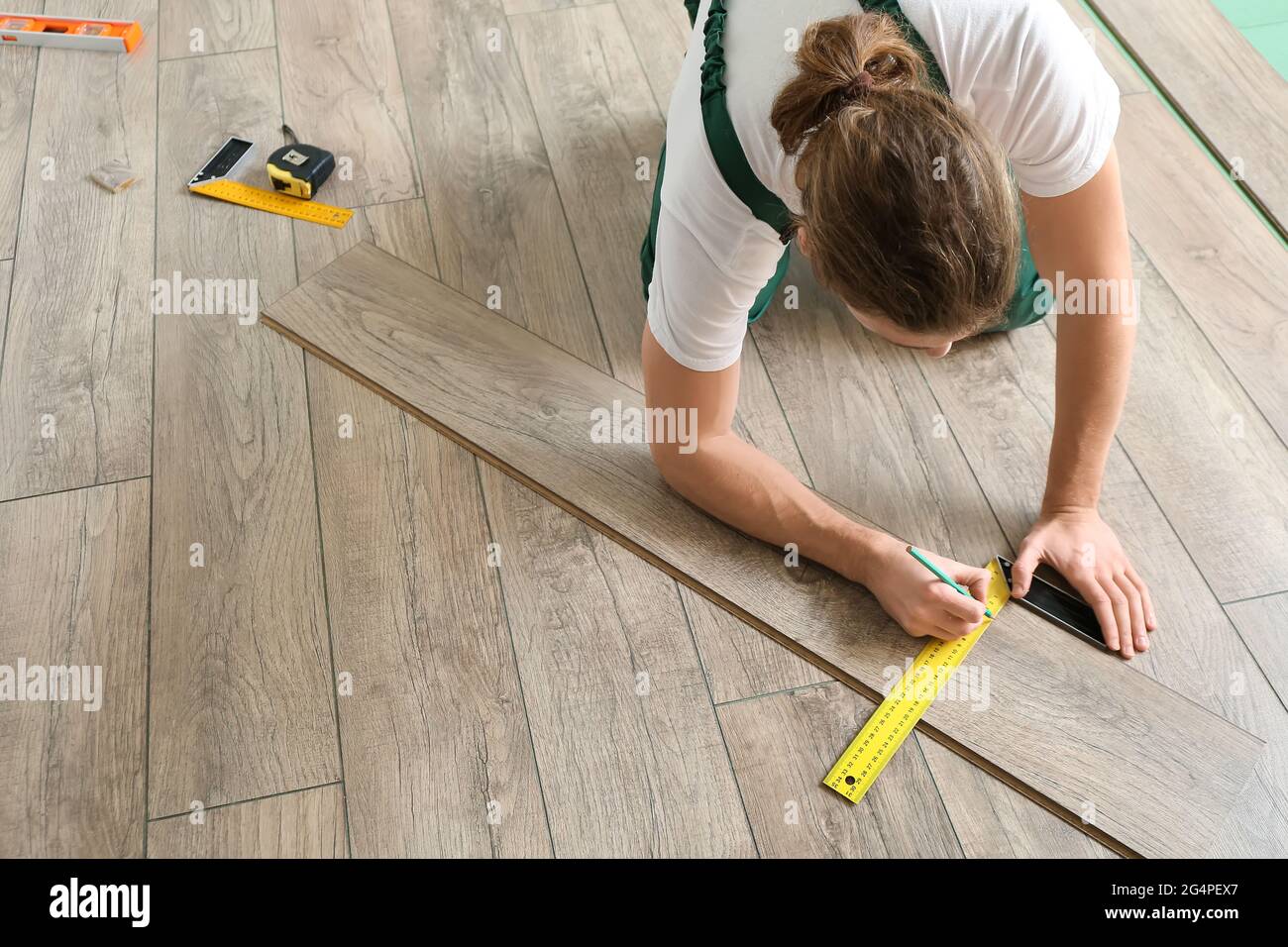 Carpenter taking measurements of laminate flooring in room Stock Photo ...