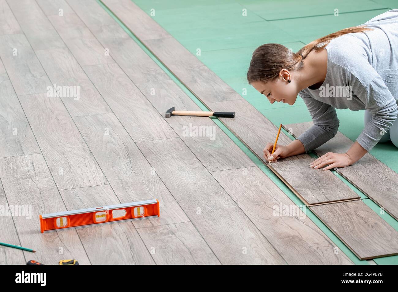 Woman installing laminate flooring in room Stock Photo - Alamy
