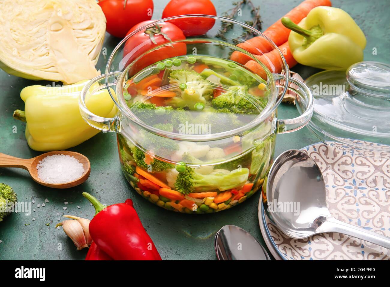 Stylish cooking pot with tasty soup and ingredients on color background ...