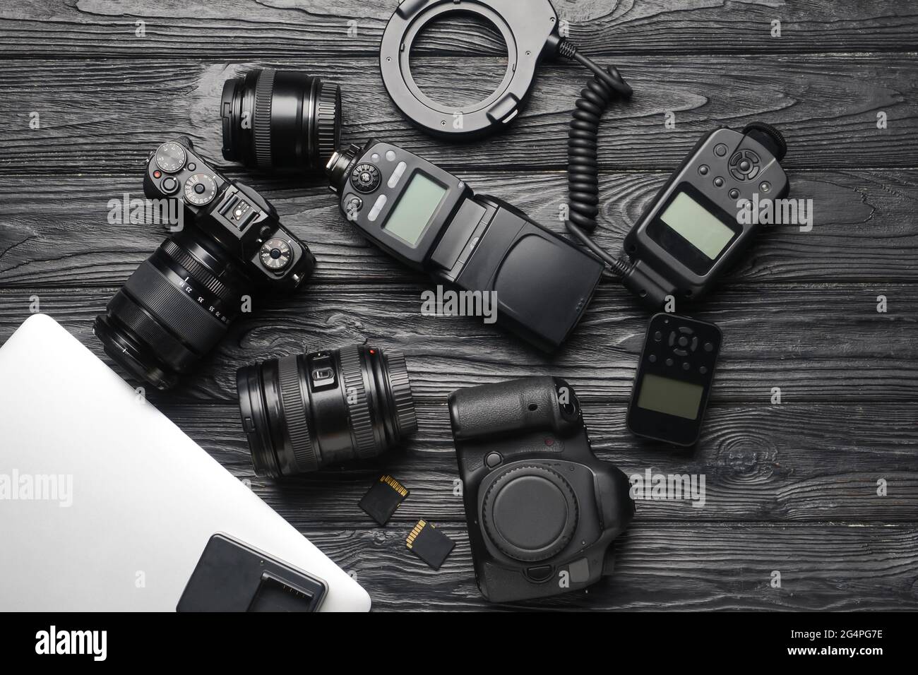 Modern photographer's equipment and laptop on dark wooden background ...