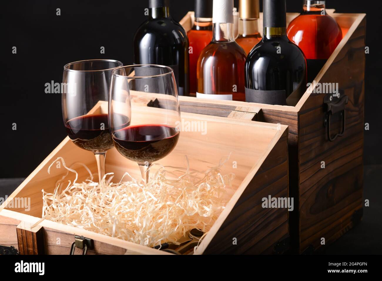 Box with bottles of wine and glasses on dark background Stock Photo - Alamy