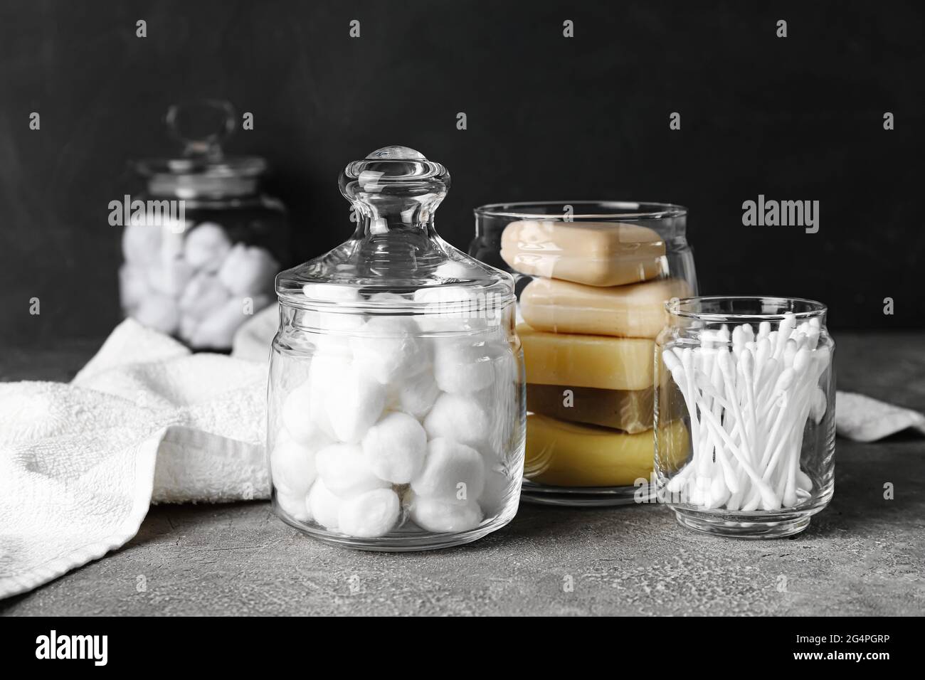 Container with soft cotton wool, soap and swabs on dark background ...