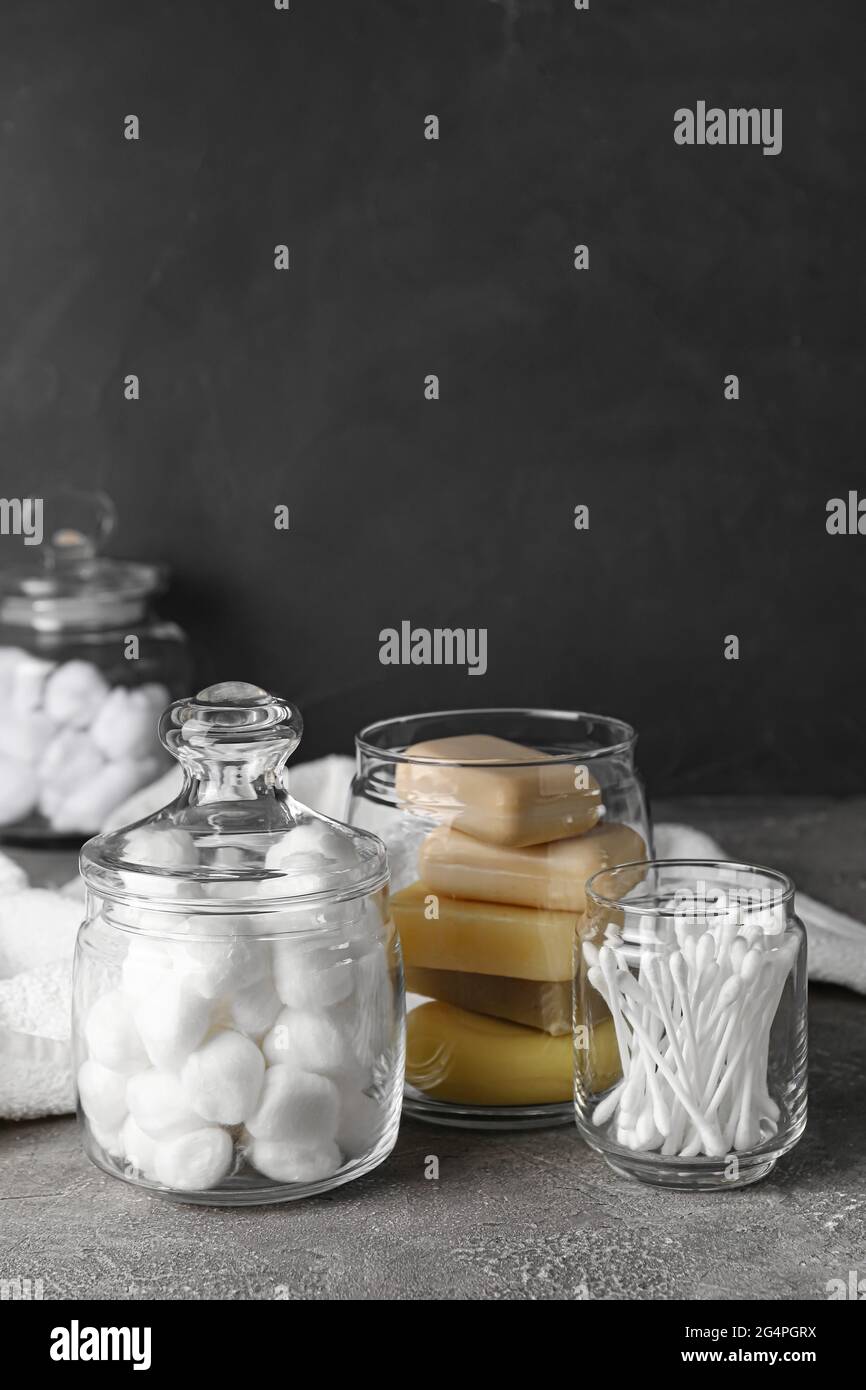Container with soft cotton wool, soap and swabs on dark background ...