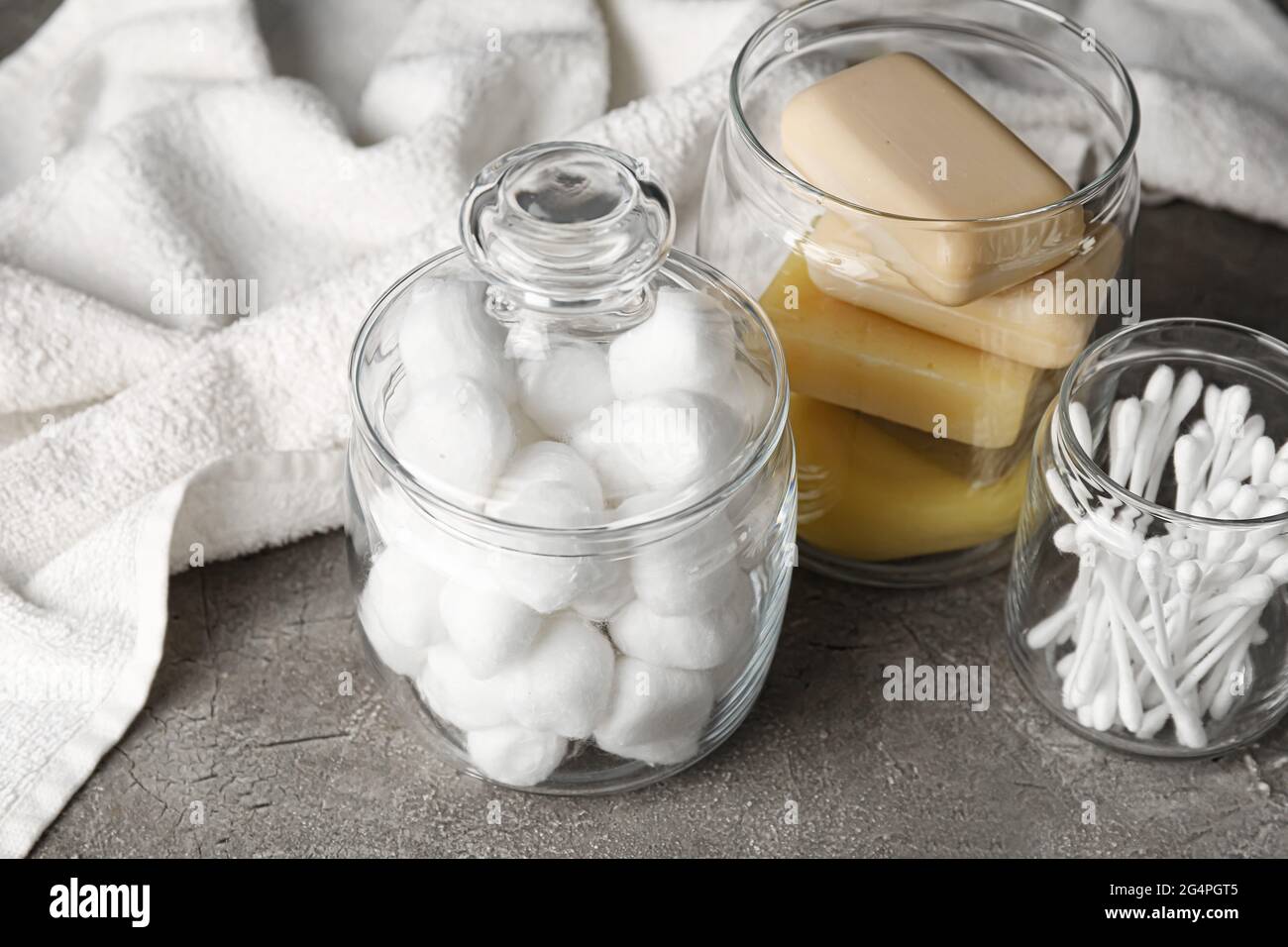 Container with soft cotton wool, soap and swabs on dark background ...