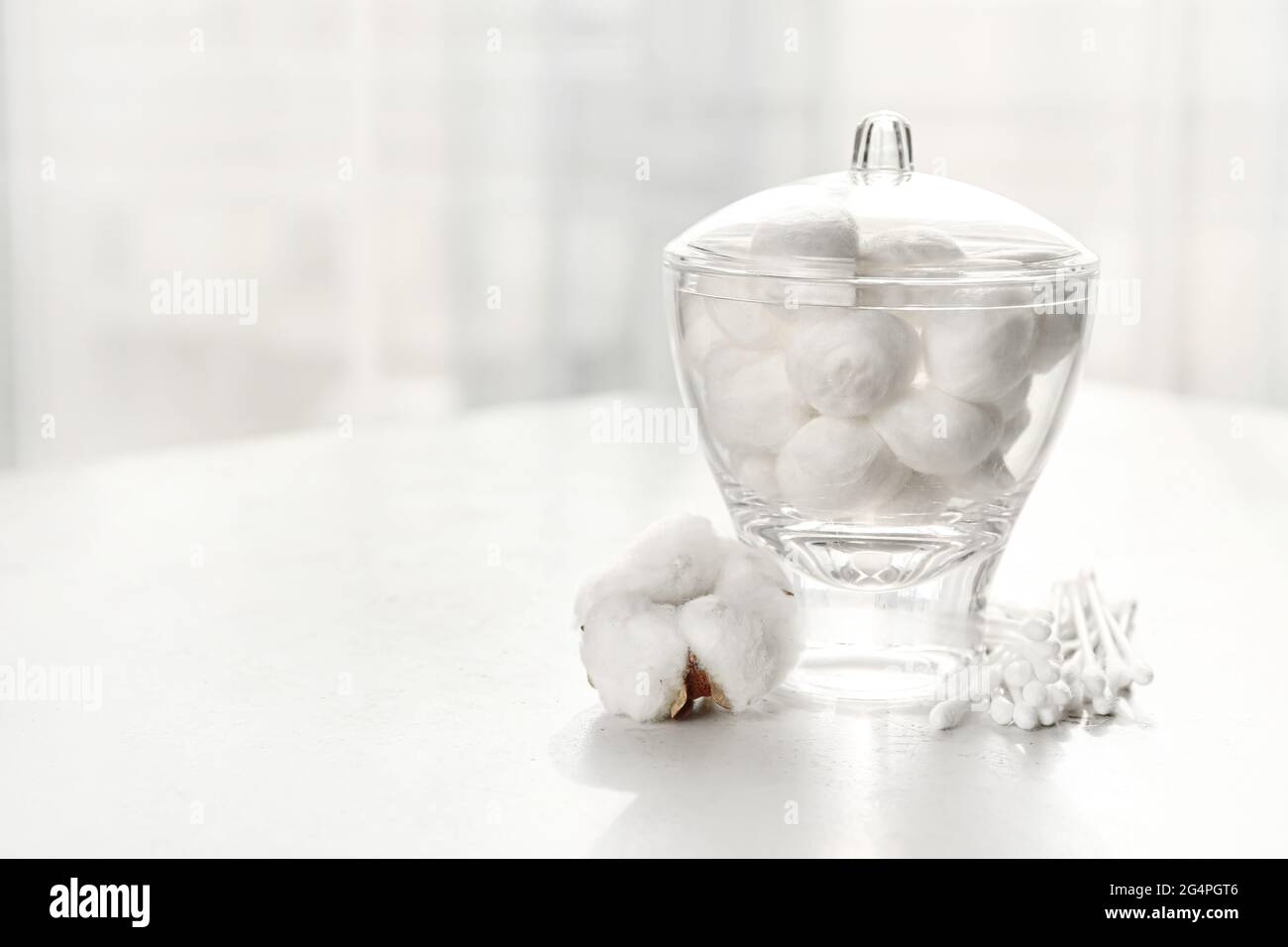 Container with soft cotton wool and swabs on table in room Stock Photo ...