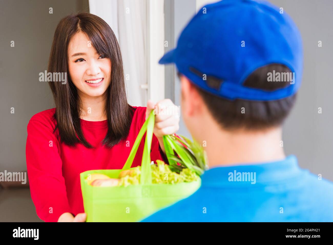 Asian young delivery man in uniform making grocery service giving fresh ...