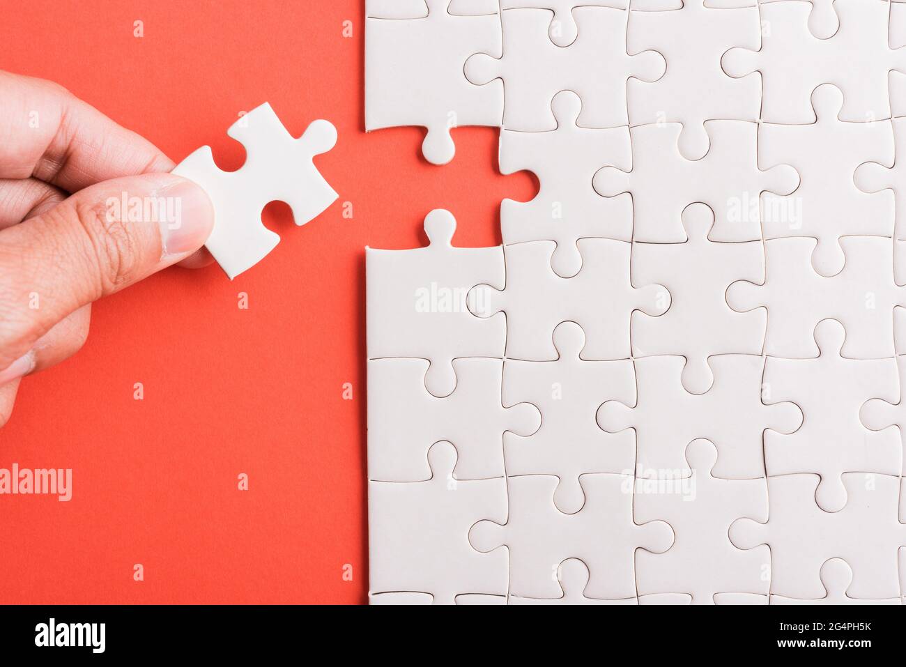 Top view flat lay of hand-holding last piece white paper jigsaw puzzle ...