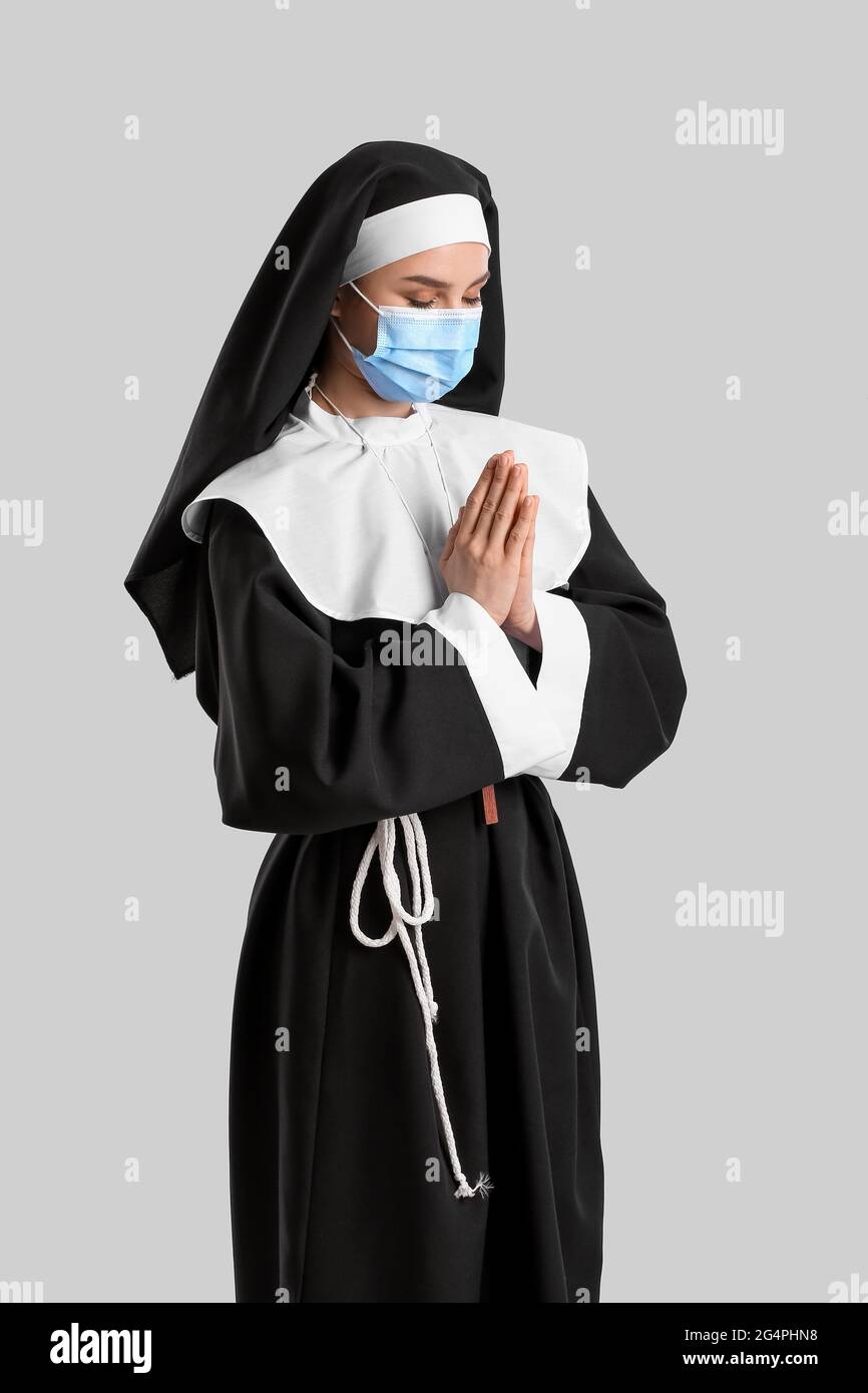 Young nun wearing medical mask on light background Stock Photo - Alamy