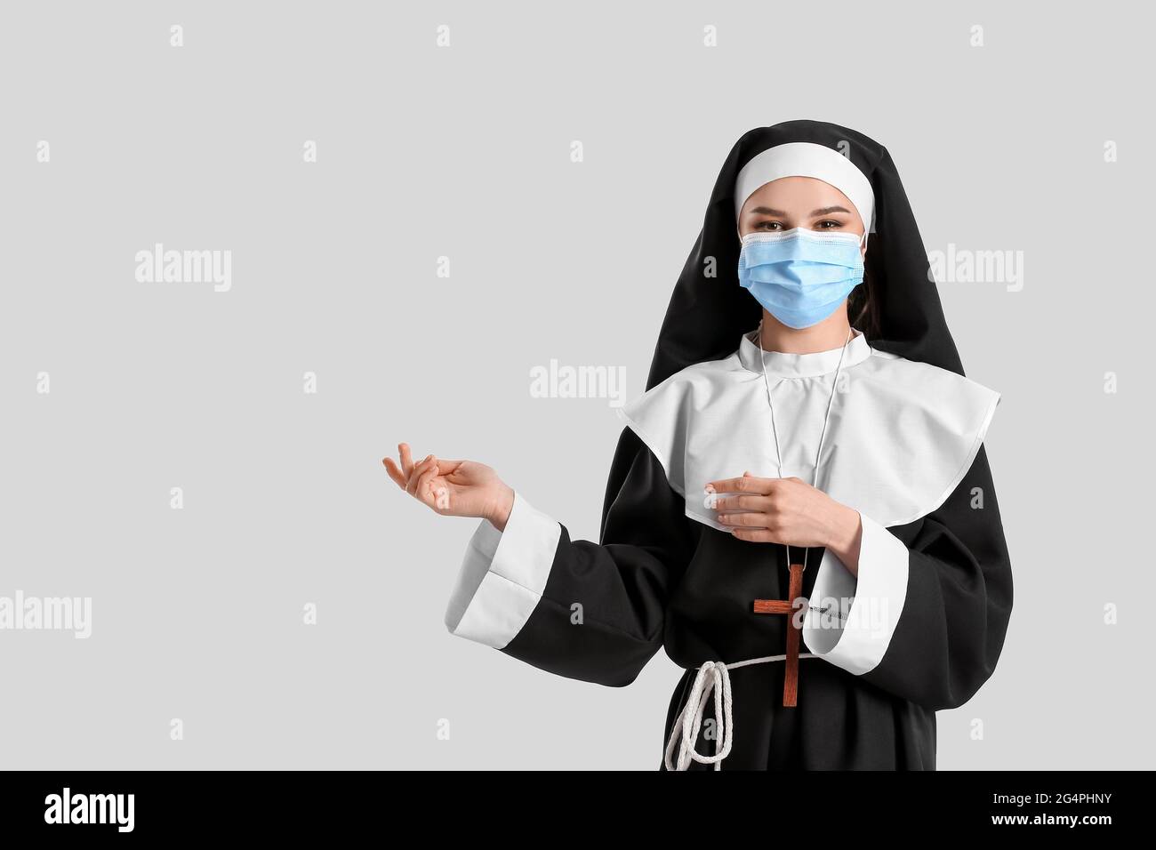 Young nun wearing medical mask on light background Stock Photo - Alamy
