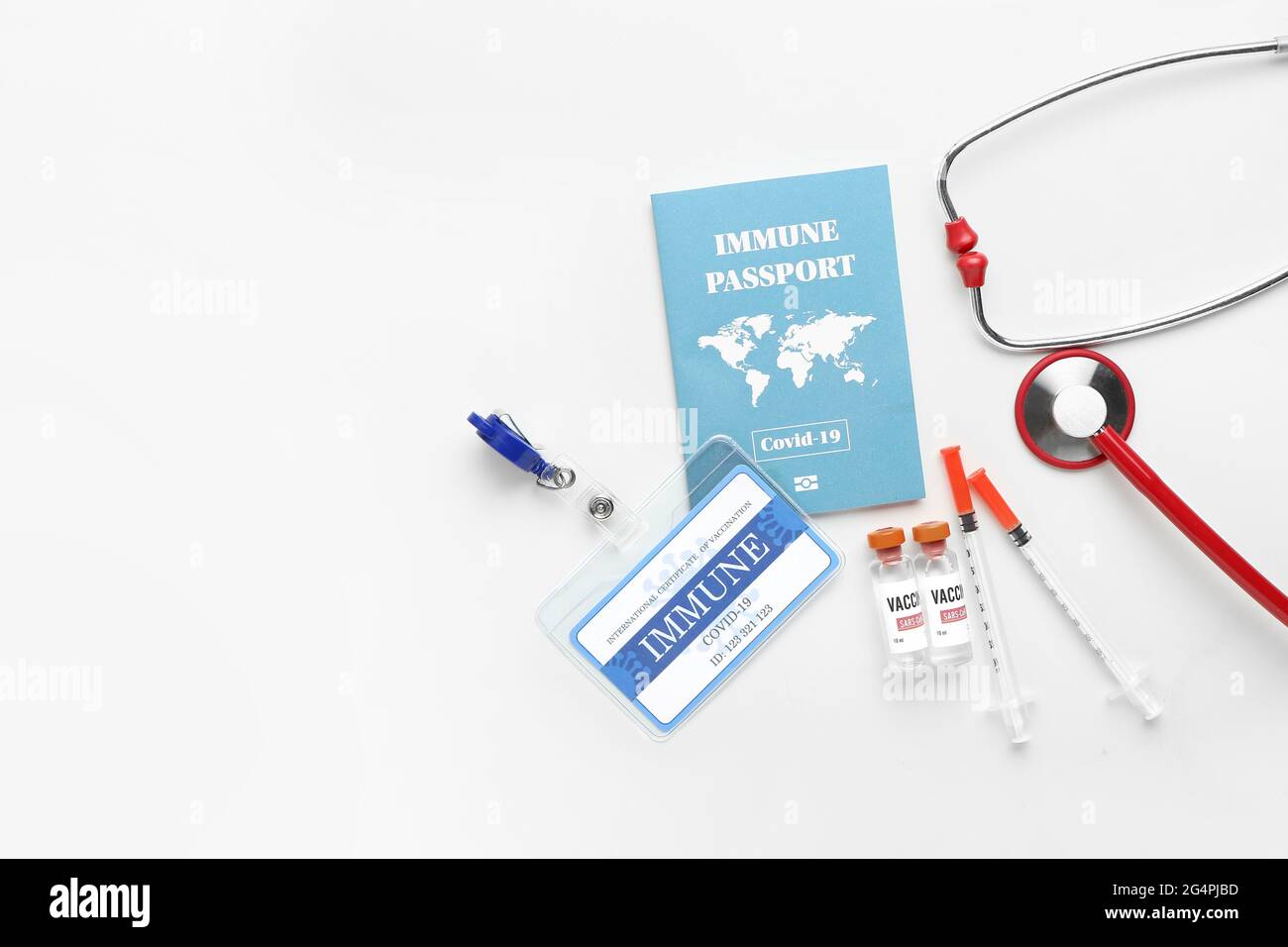 Immune card, passport, covid-19 vaccine and stethoscope on white ...