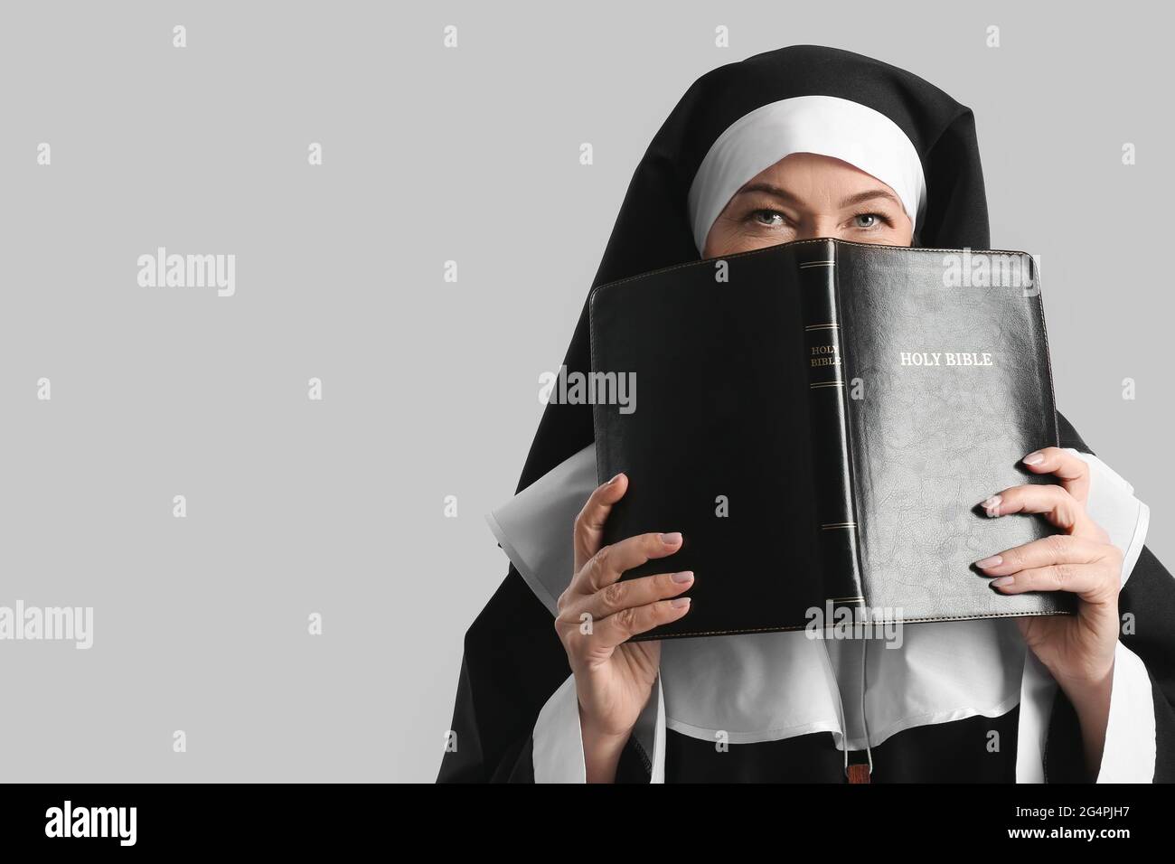 Mature nun with Holy Bible on grey background Stock Photo - Alamy