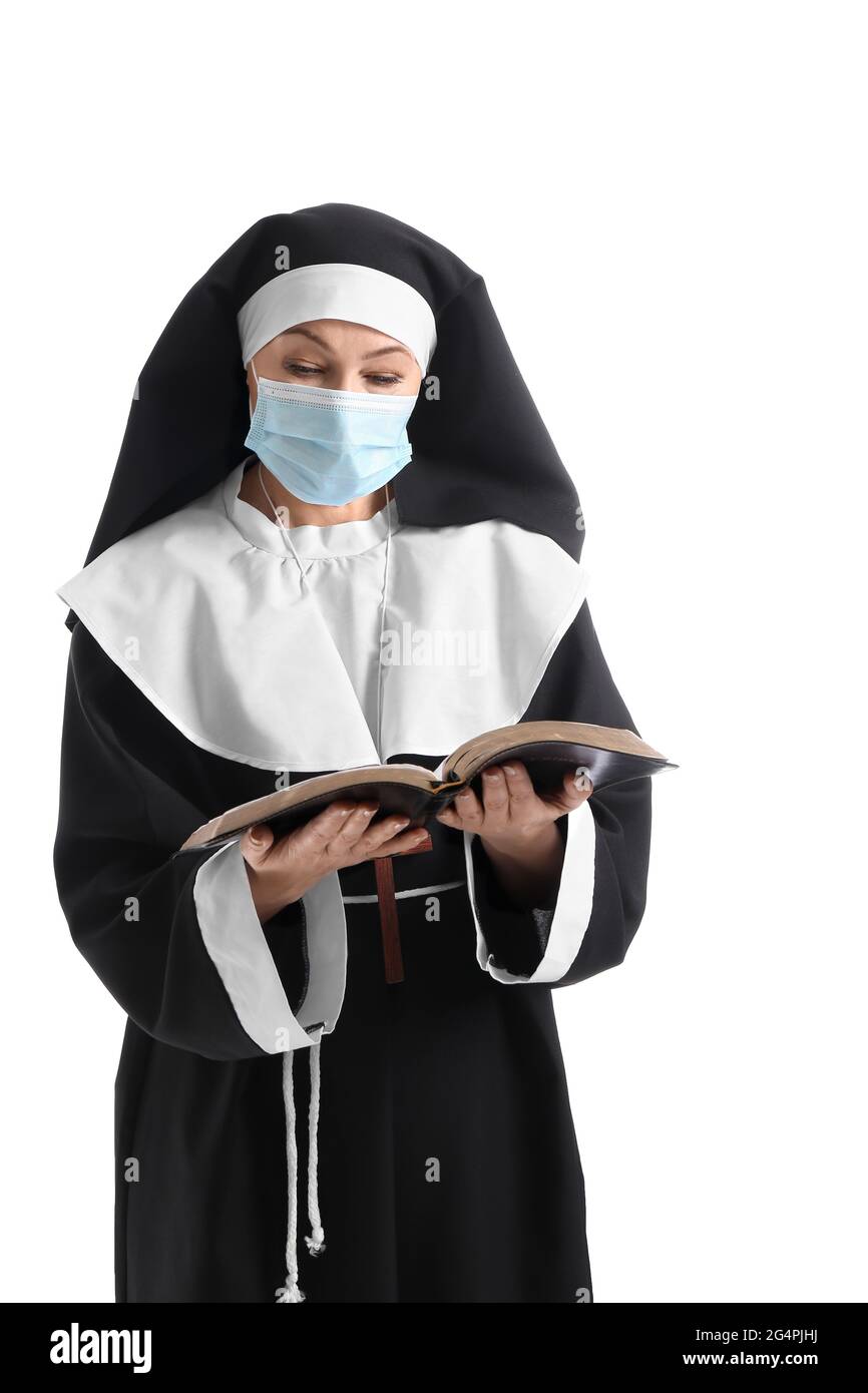 Mature nun in medical mask and with Holy Bible on white background ...