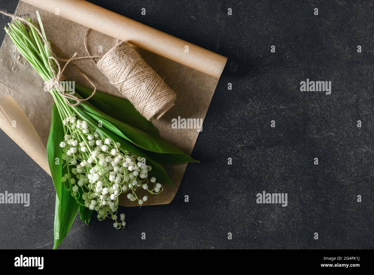 Beautiful lily-of-the-valley flowers, parchment and rope on dark ...