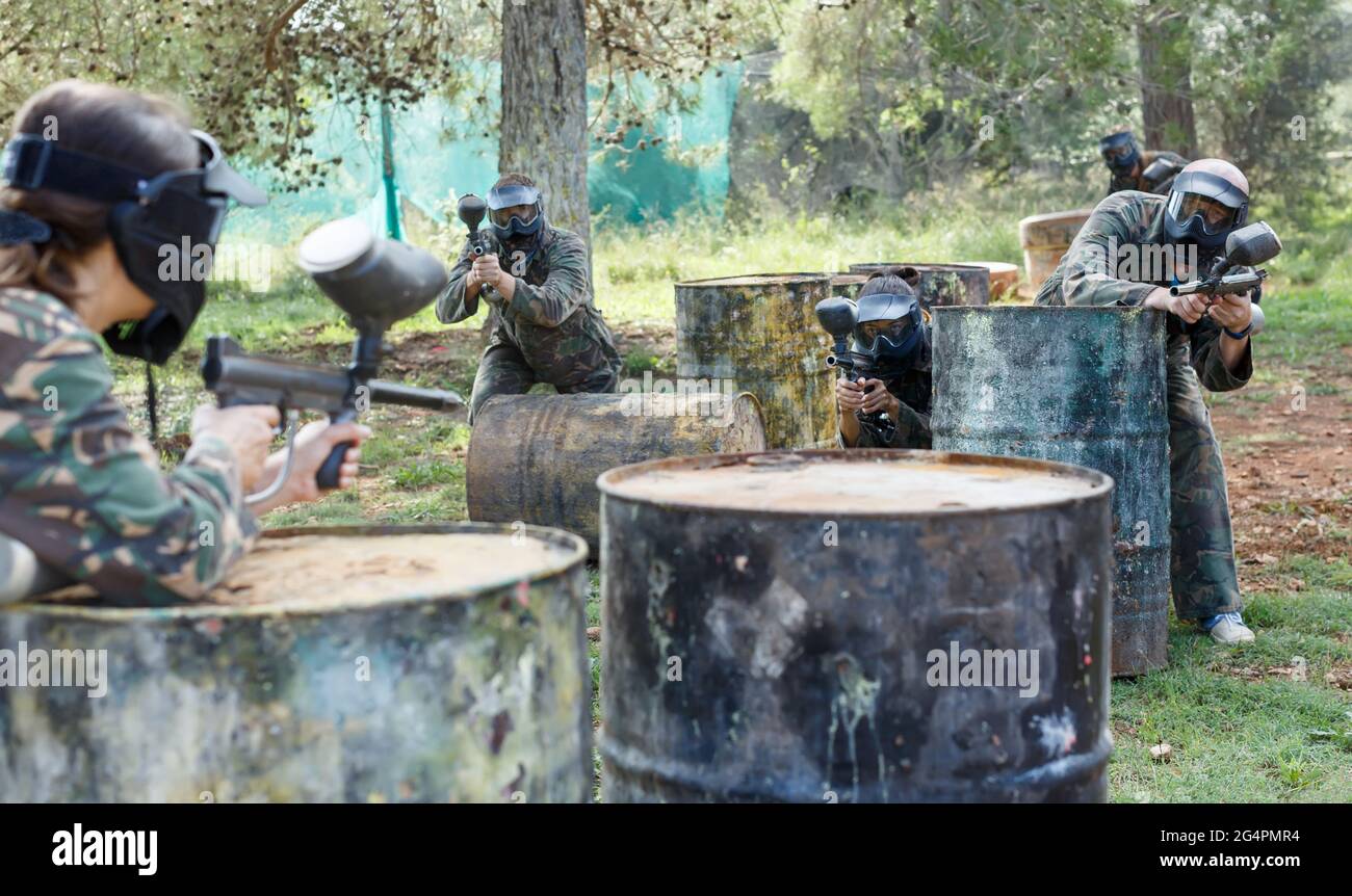 enthusiastic teams facing on battlefield in outdoor paintball arena ...