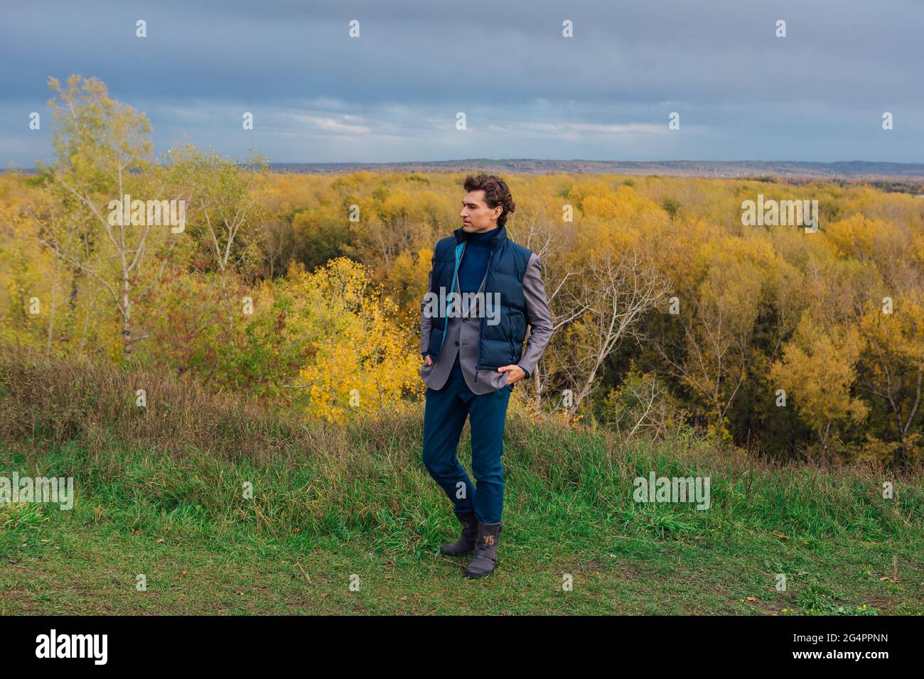 Tall handsome man walking outdoor in yellow autumn forest on the hill ...