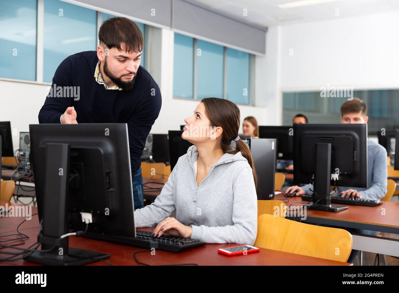 Teacher helping student in computer class Stock Photo - Alamy