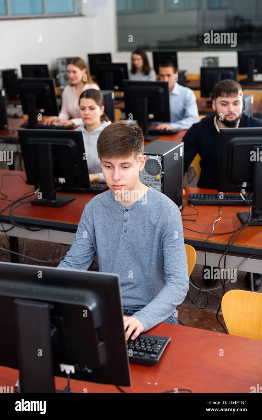 Portrait of female and male students working on computers in classroom ...