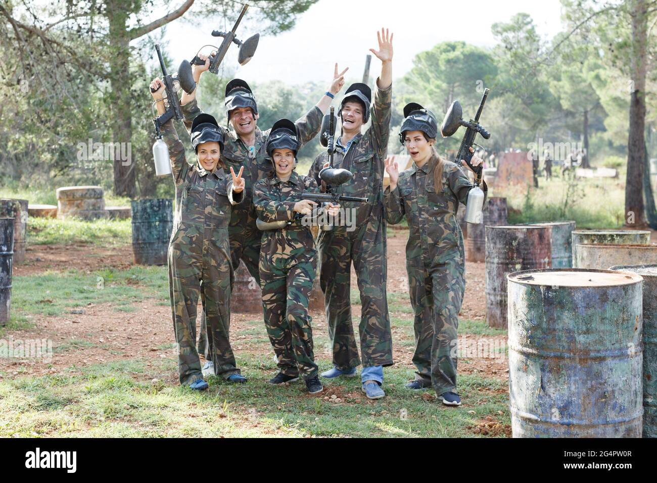 Portrait of happy friends paintball players in uniform holding guns ...