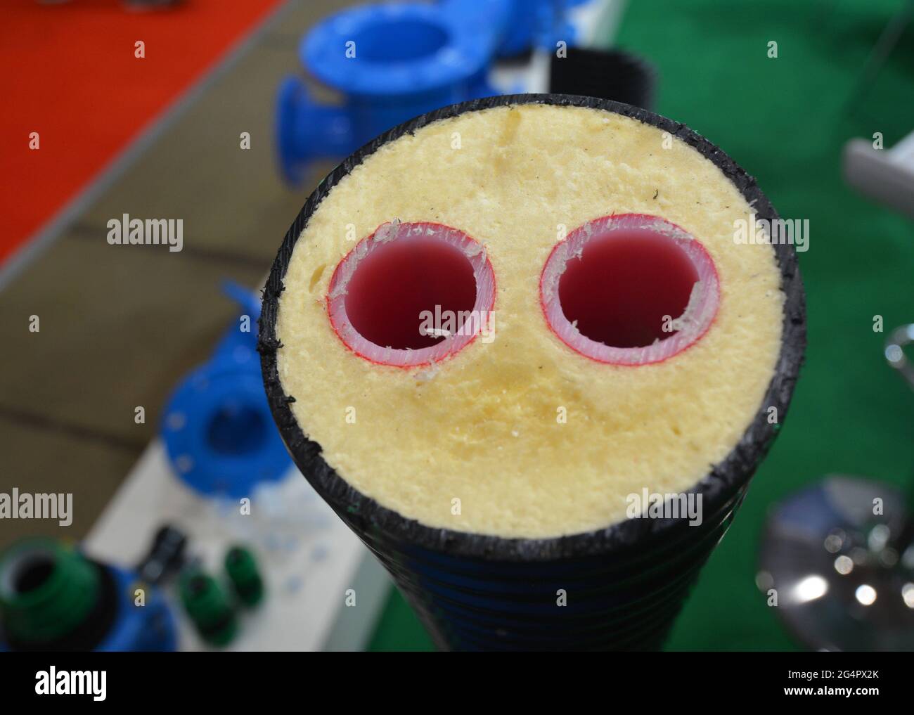 A close-up of red hot water plastic pipes, PEX tubing, insulated in one ...