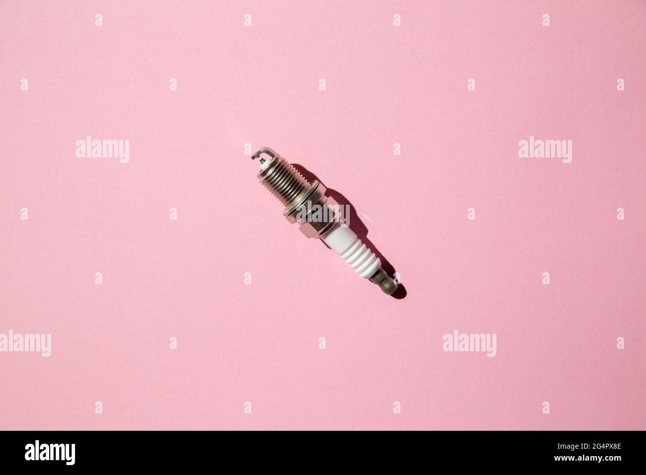 Spark plug. Car candle lies against a pink background. Auto engine ...