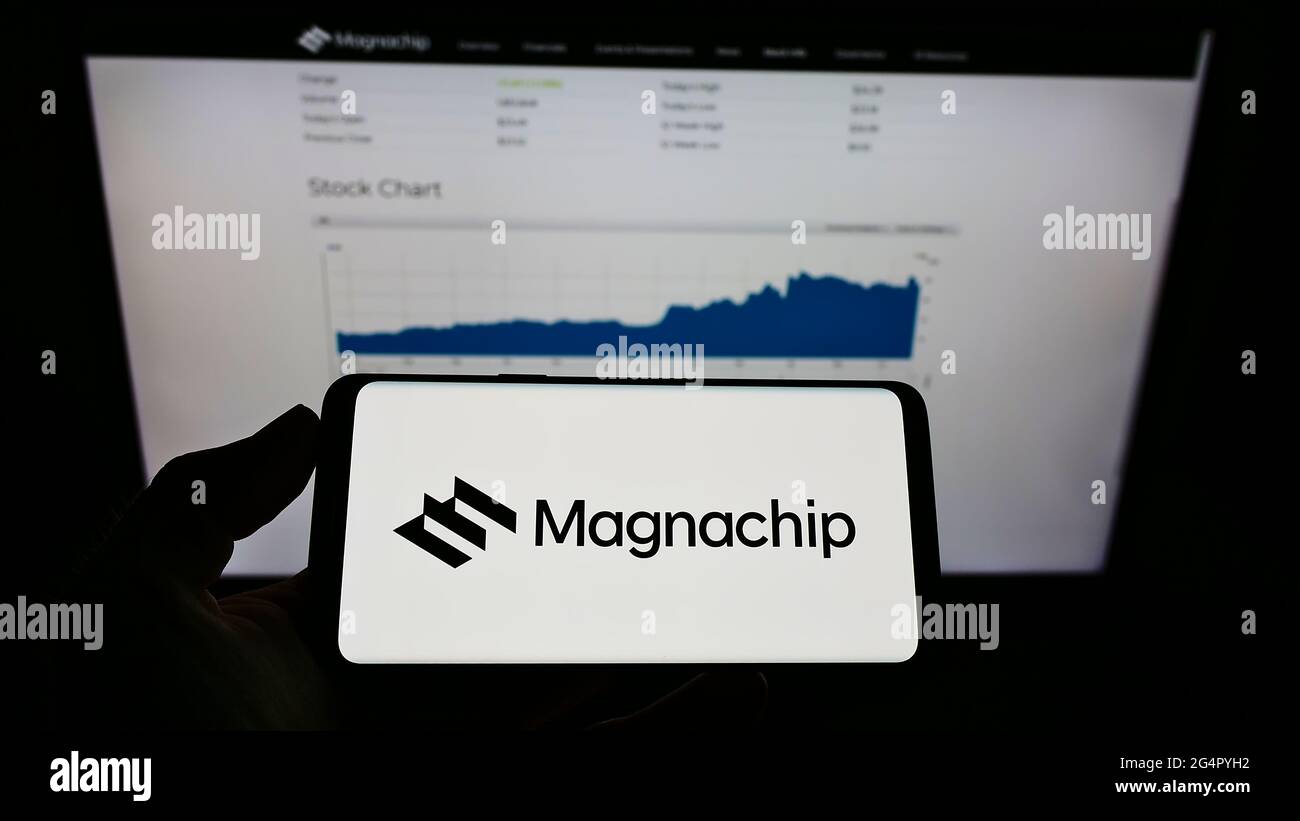Person holding mobile phone with logo of company MagnaChip ...