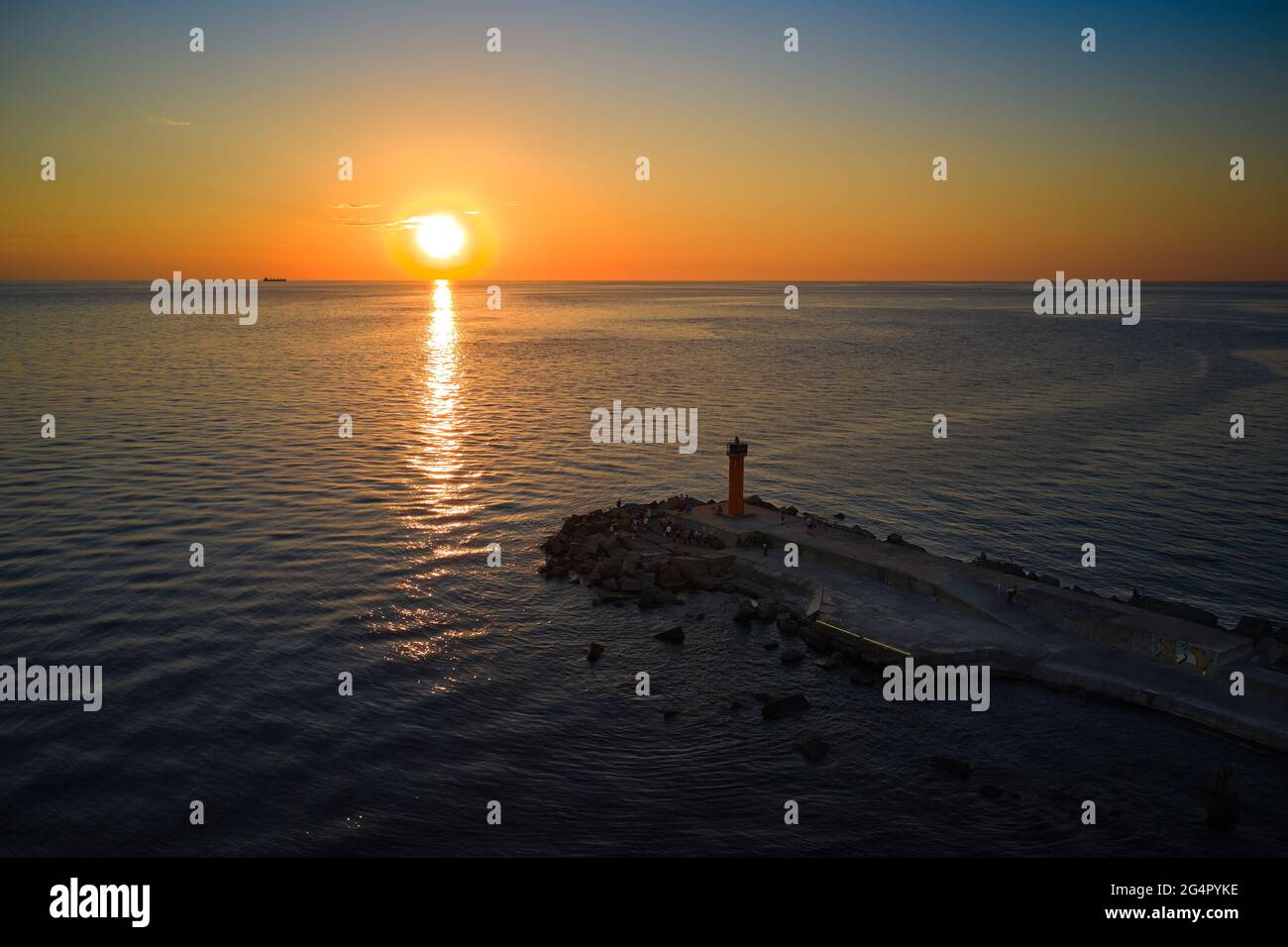 Amazing sunset sky and long stone pier with lighthouse Stock Photo - Alamy