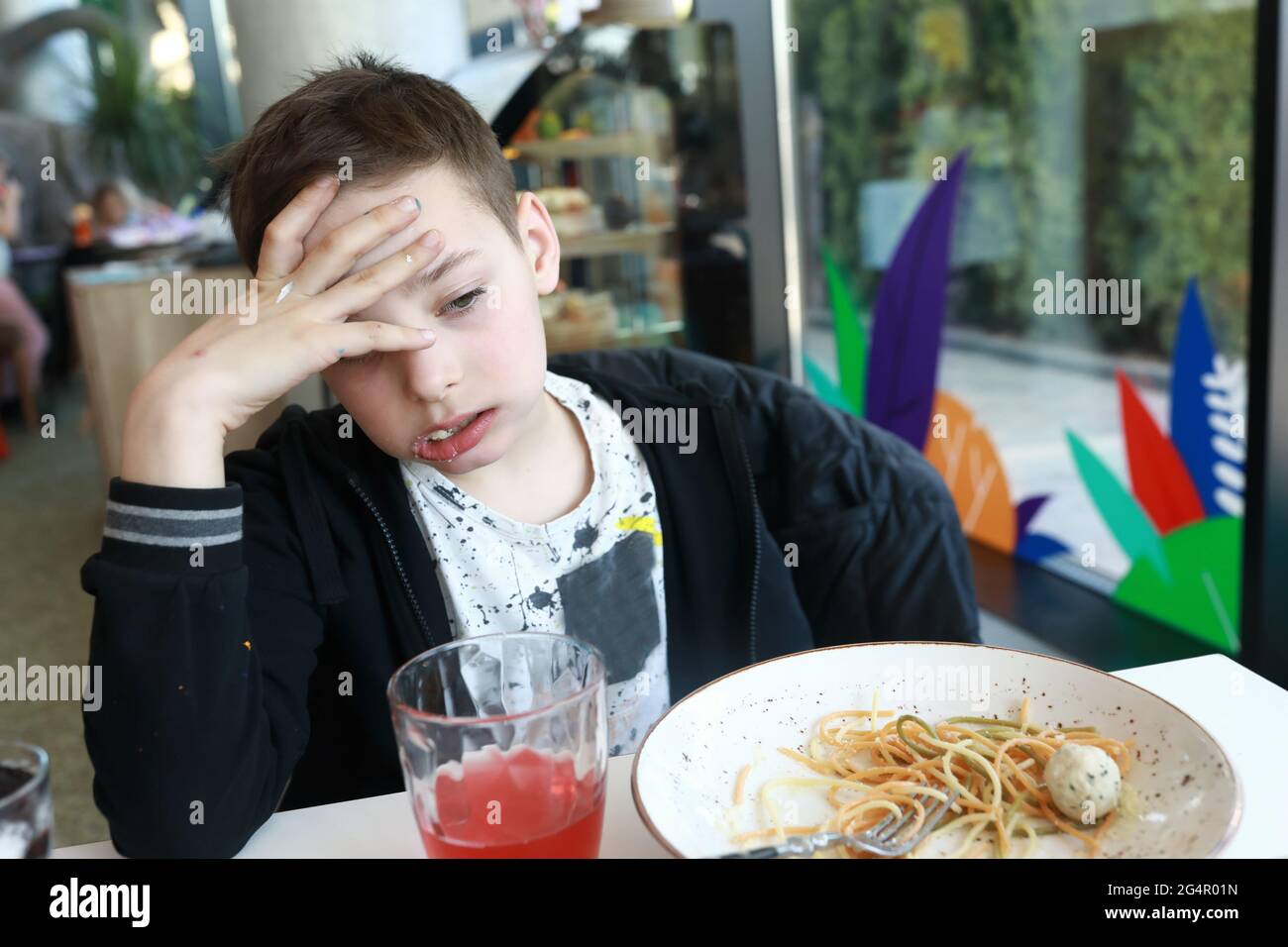 Child is tired of eating in restaurant Stock Photo - Alamy