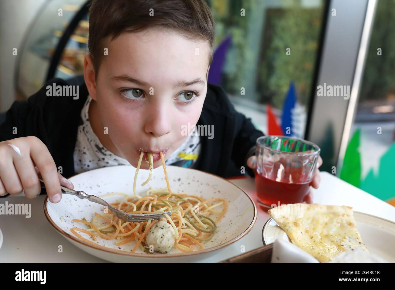 Boy has spaghetti with chicken meatballs in restaurant Stock Photo - Alamy