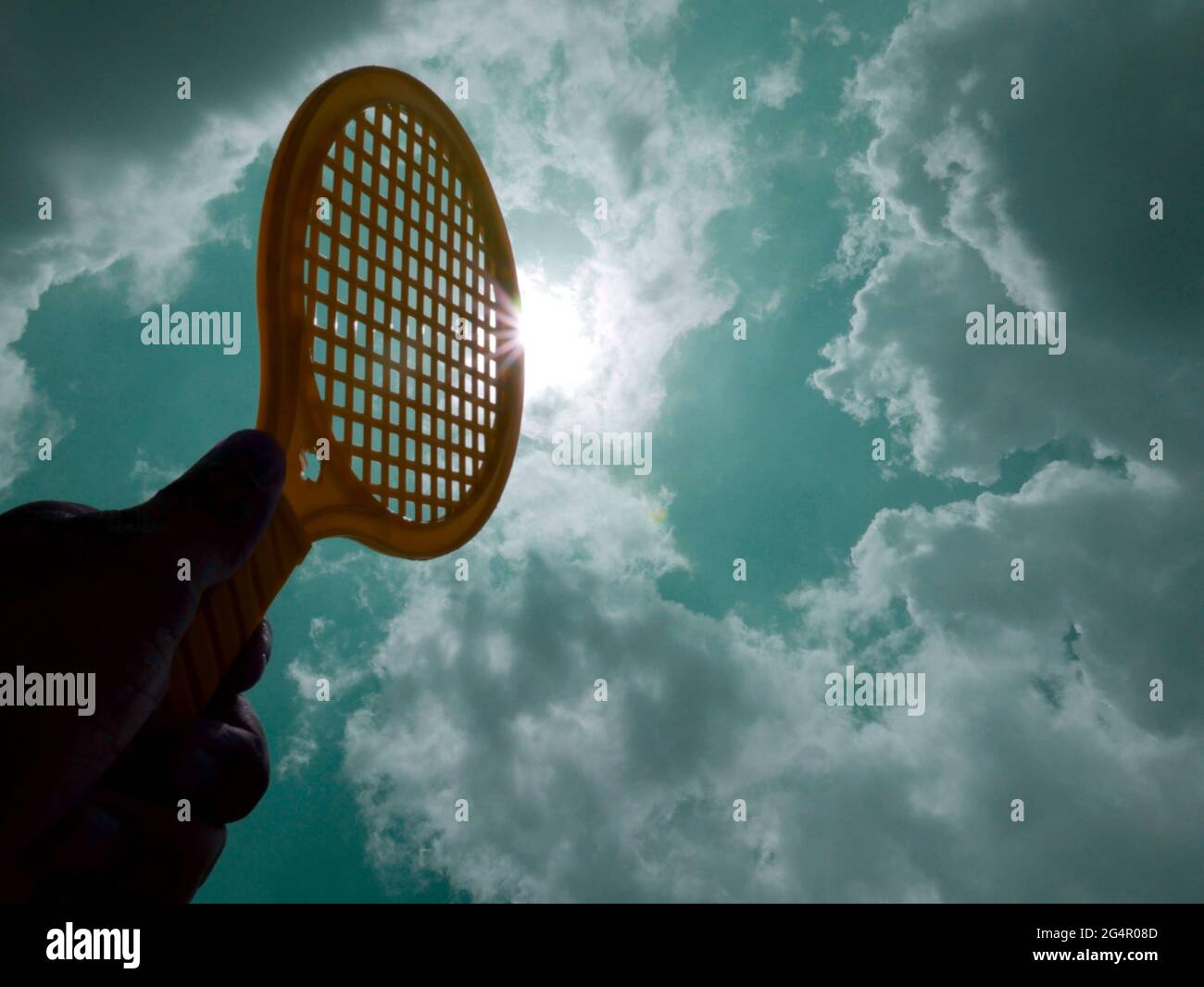 badminton racket holding on hand towards sun light on sky background ...