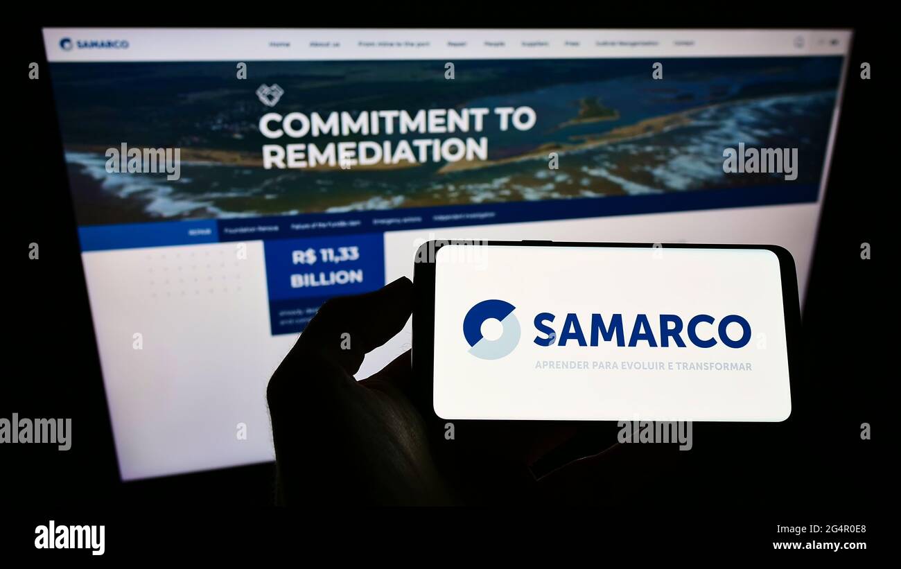 Person holding mobile phone with logo of Brazilian mining company ...