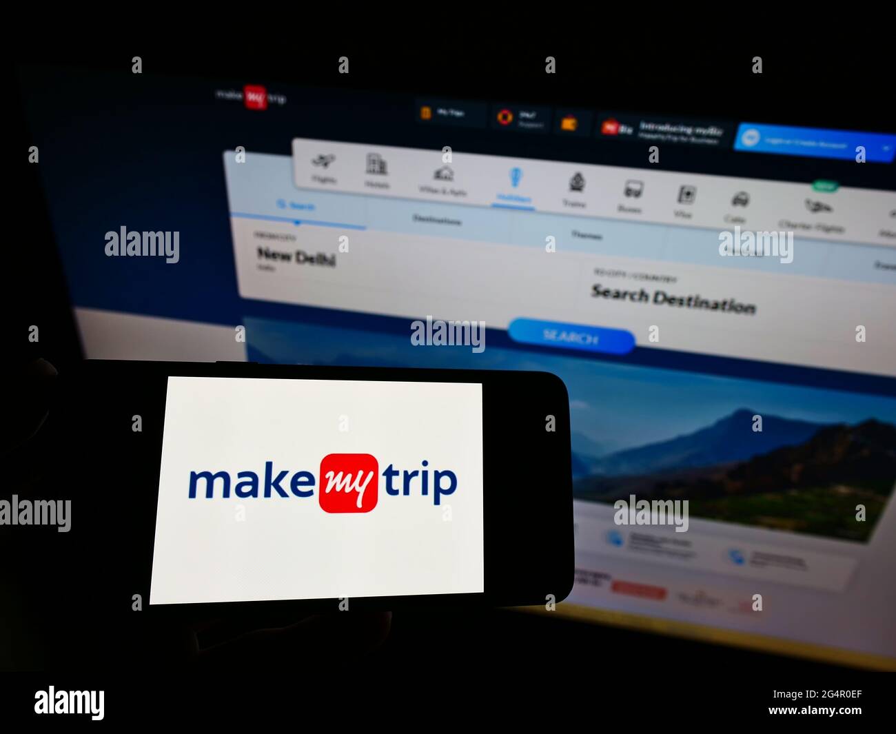 Person holding mobile phone with logo of Indian online travel company ...