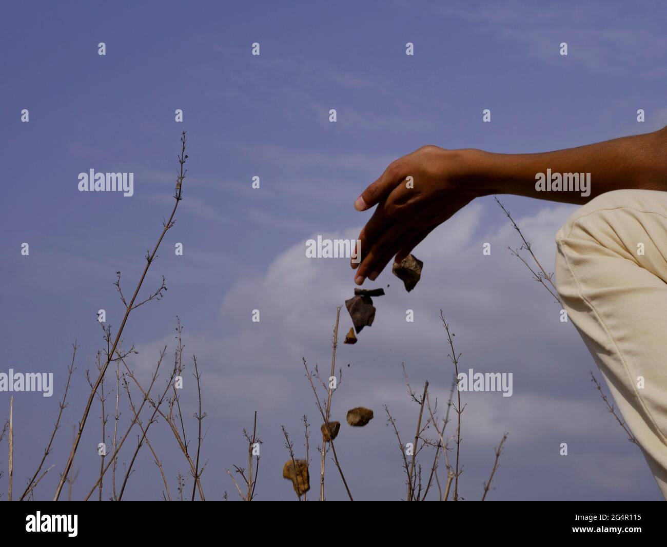 Stone pieces falling down from boy hand on sky background Stock Photo ...