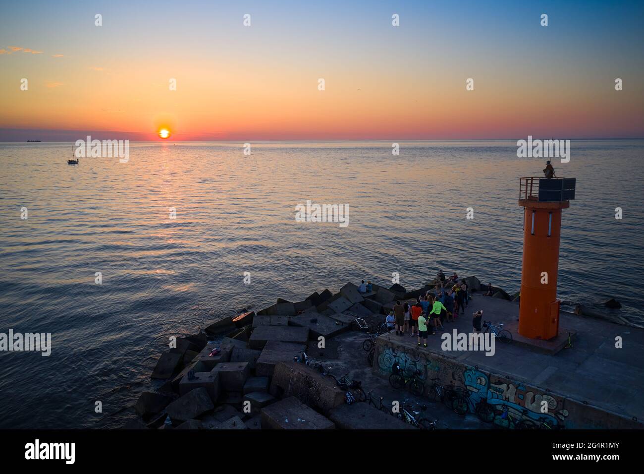 Amazing sunset sky and long stone pier with lighthouse Stock Photo - Alamy