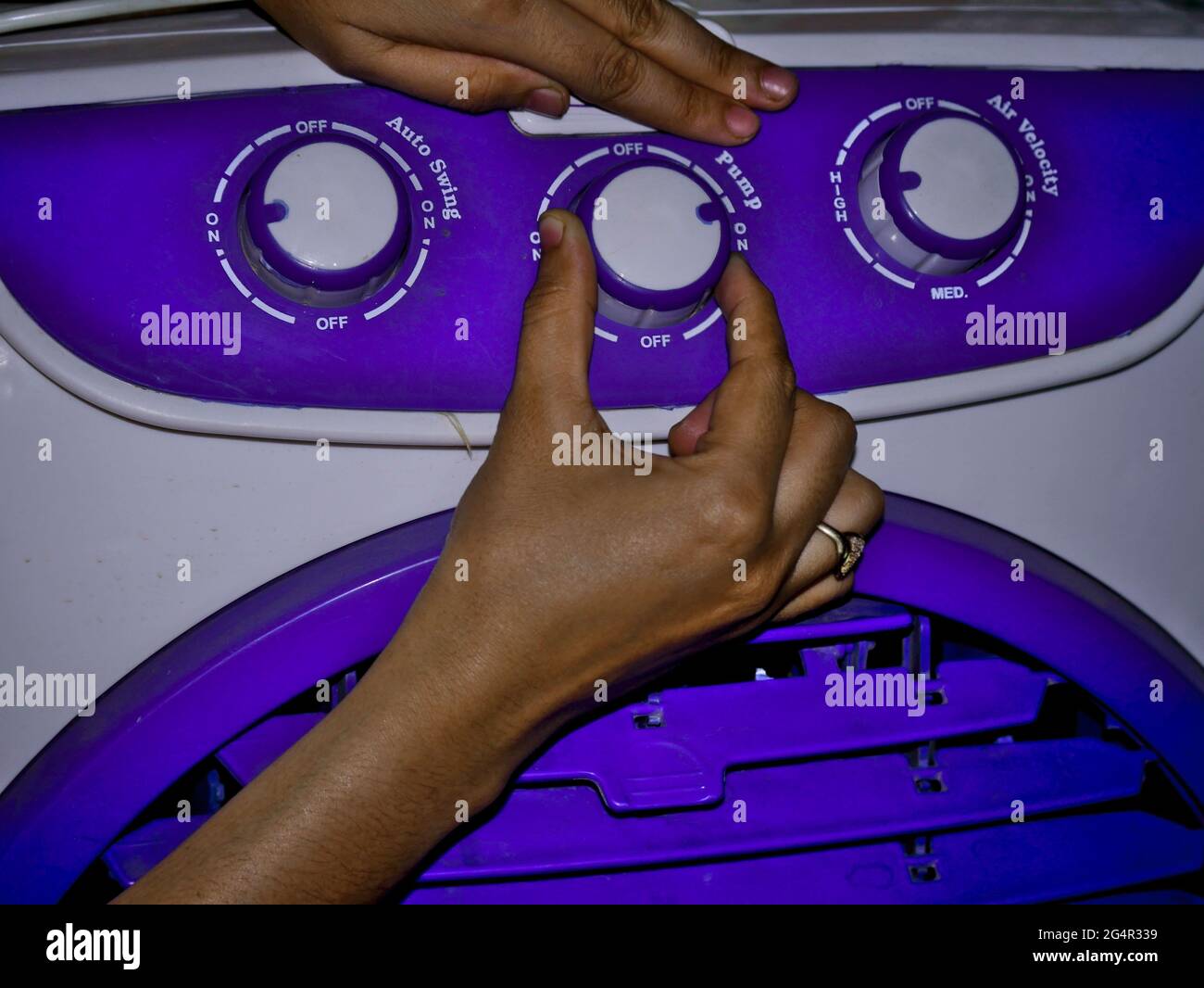 Female hand operating air cooler button, technology at home concept ...
