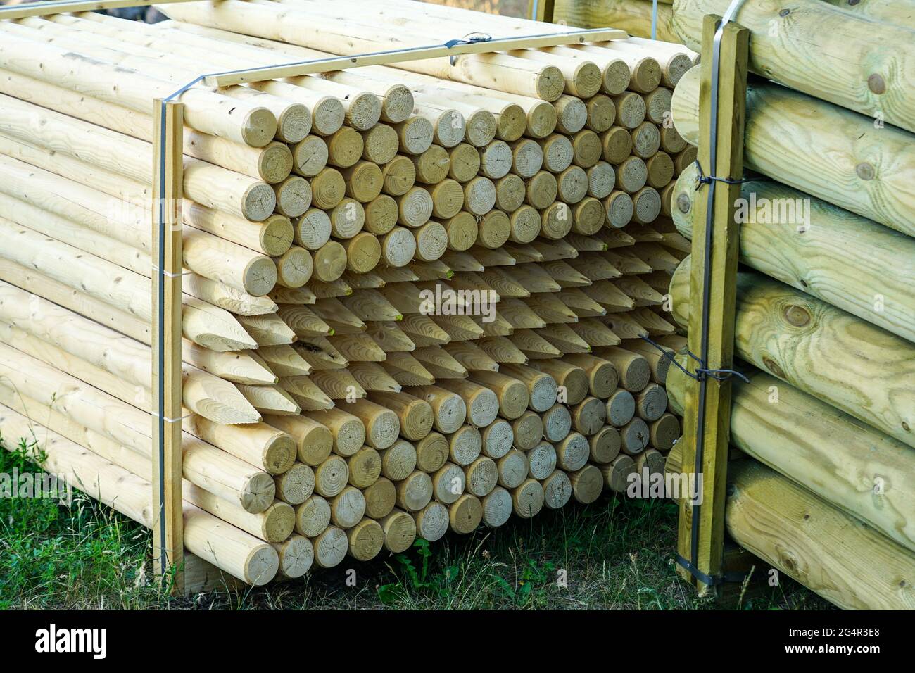 pallet with long round natural wooden fence posts with a sharpened tip ...