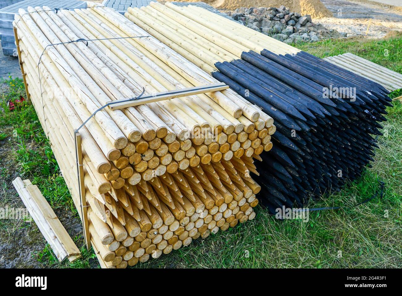 two pallets with long round natural wooden fence posts with tarred and ...