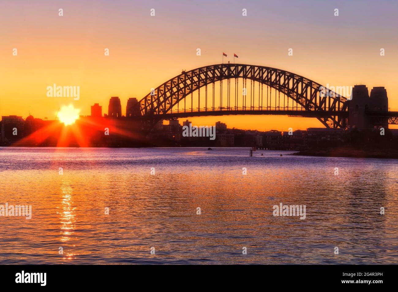 Rising sun over horizon behind the Sydney Harbour bridge blasting ...