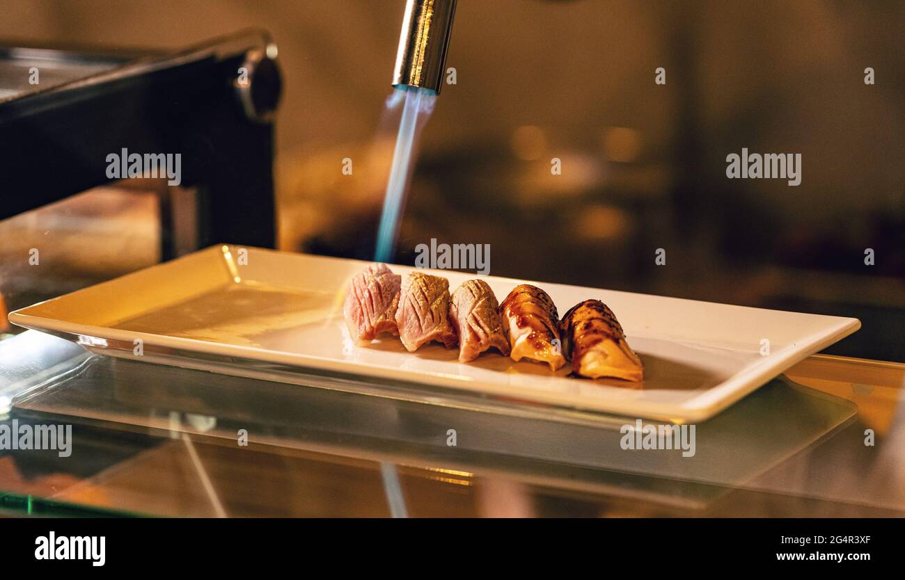 Chef cooking salmon sushi, fusion Japanese cuisine food, using gas ...