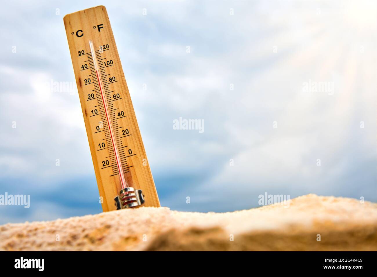 Weather thermometer in the sand against the sky showing a high ambient ...