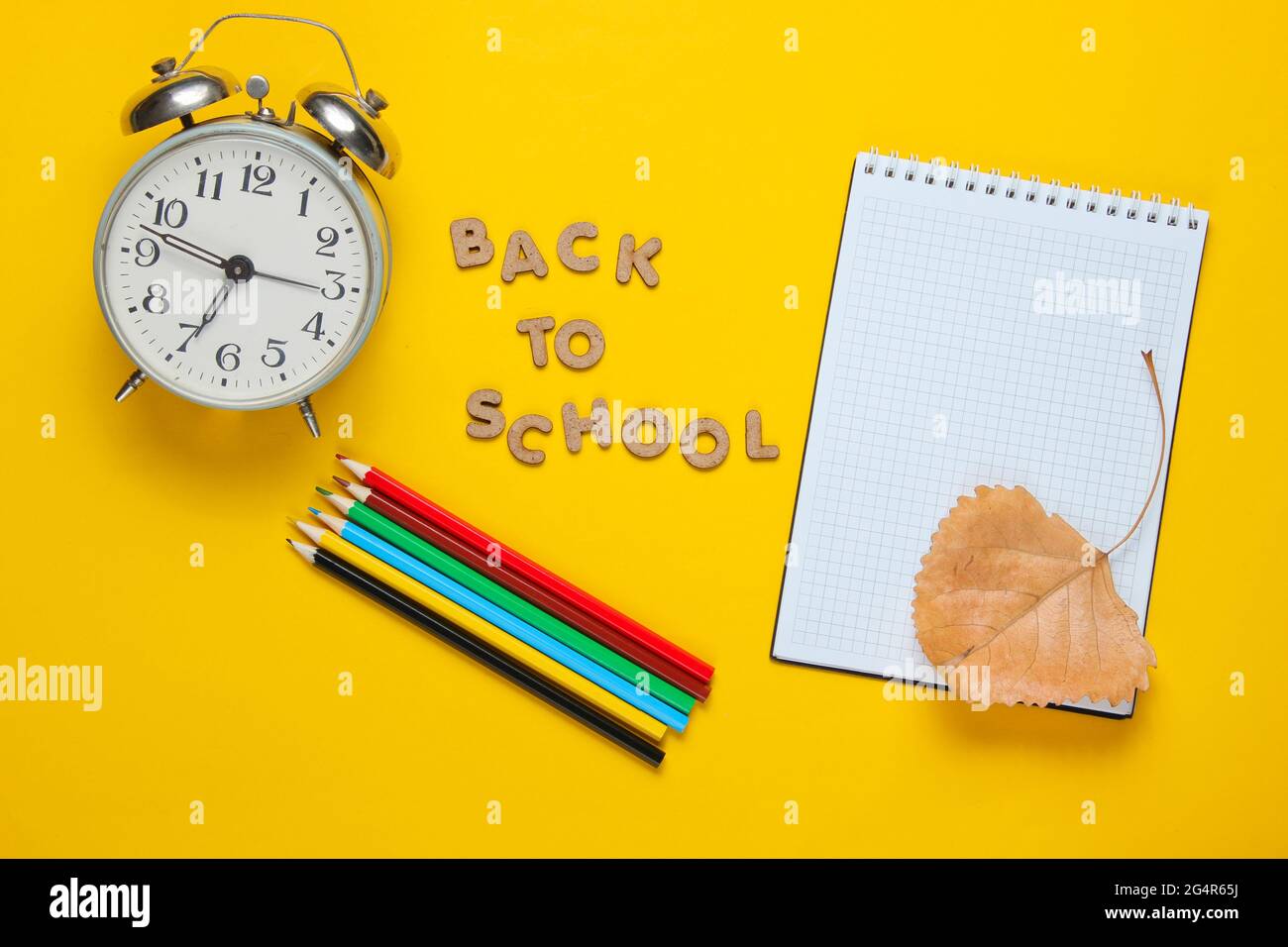 School time minimal concept. Notepad, colored pencils, alarm clock on ...