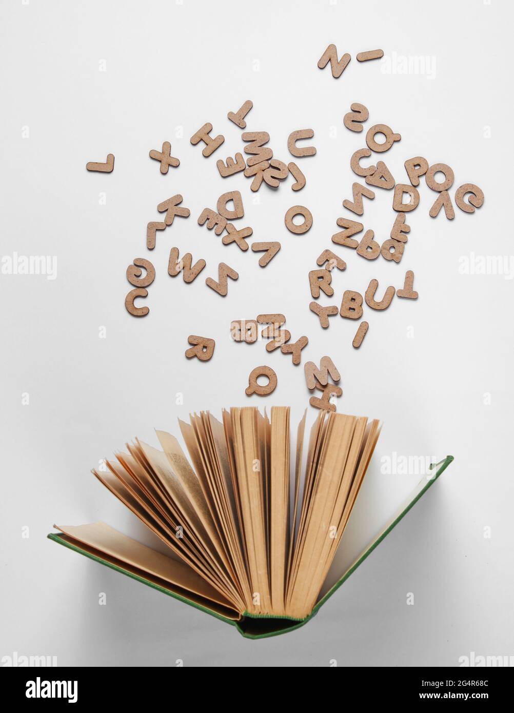 Open old book with scattered letters on white background. Top view ...
