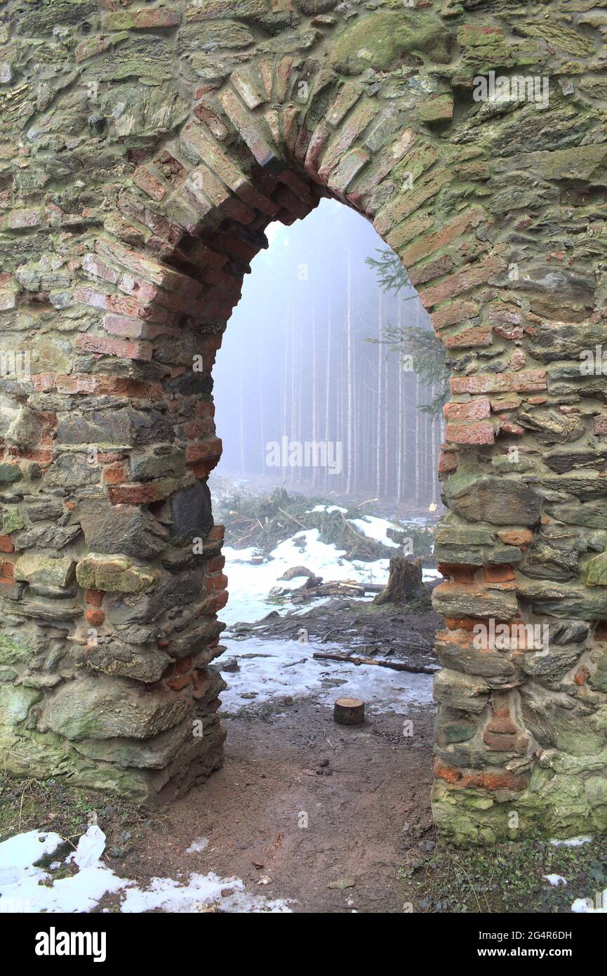 Vertical shot of an old, mossy brick gateway in the snowy woods with ...