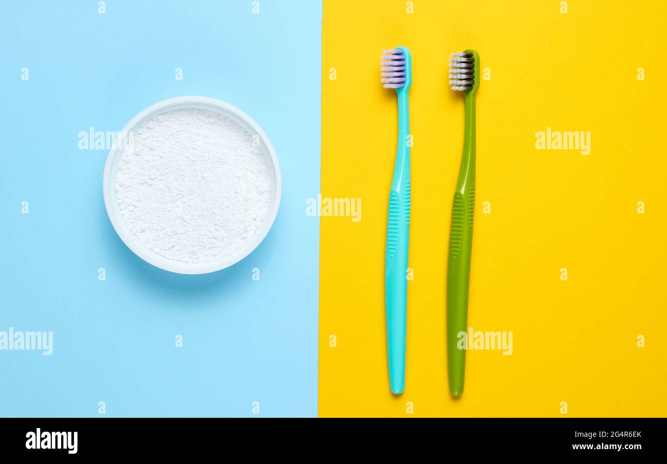 Two toothbrushes, tooth powder on yellow blue background. Minimalism ...