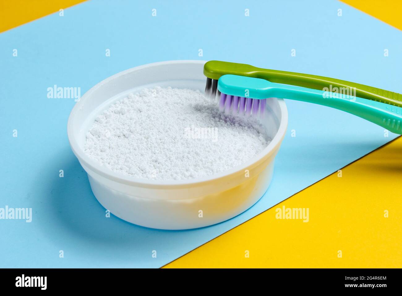 Two toothbrushes, tooth powder on yellow blue background. Minimalism ...