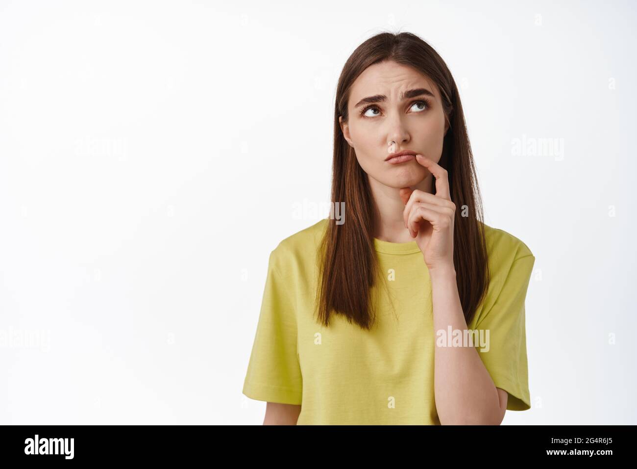 Hmm what to do. Thoughtful young woman looks up and thinks, makes ...