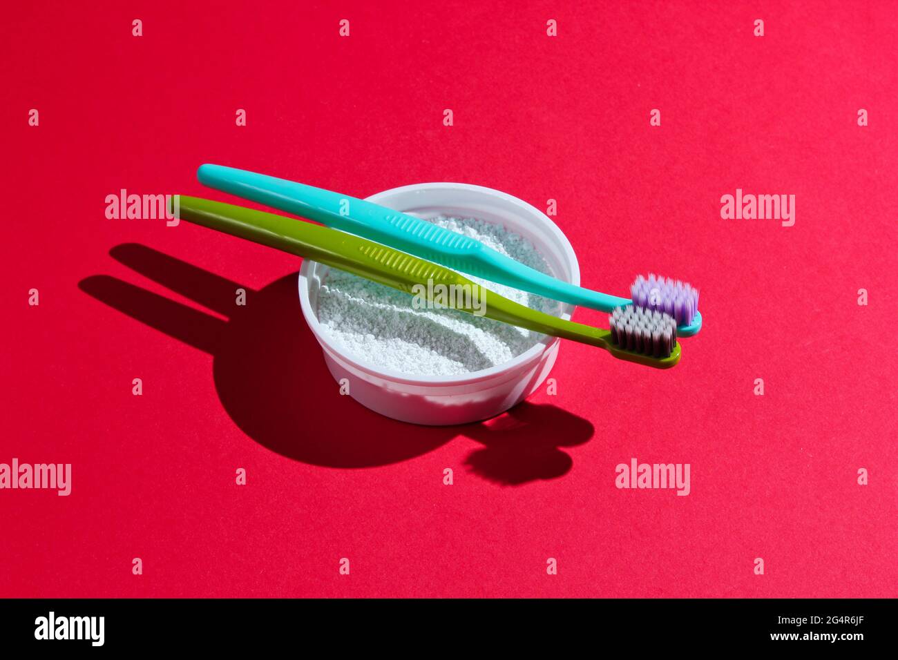 Two toothbrushes, tooth powder on red background. Minimalism oral ...